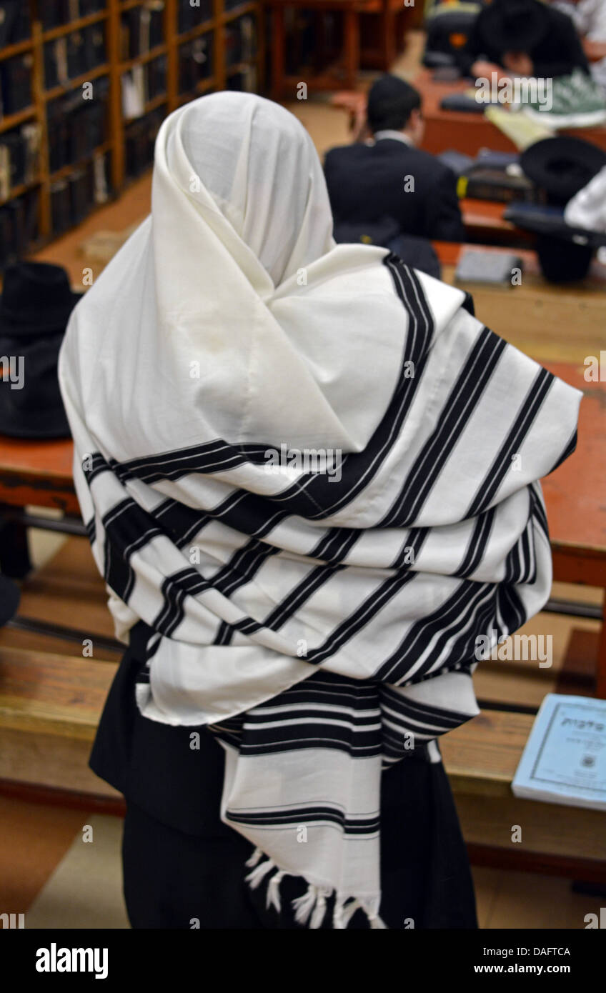A religious Jewish man putting on & blessing his tallis at morning ...
