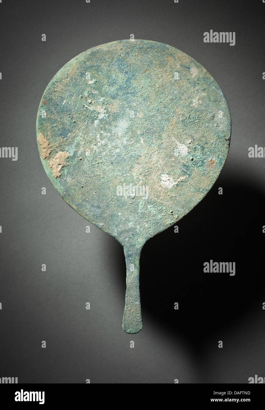 This ancient mirror, crafted from polished metal, reflects the ...