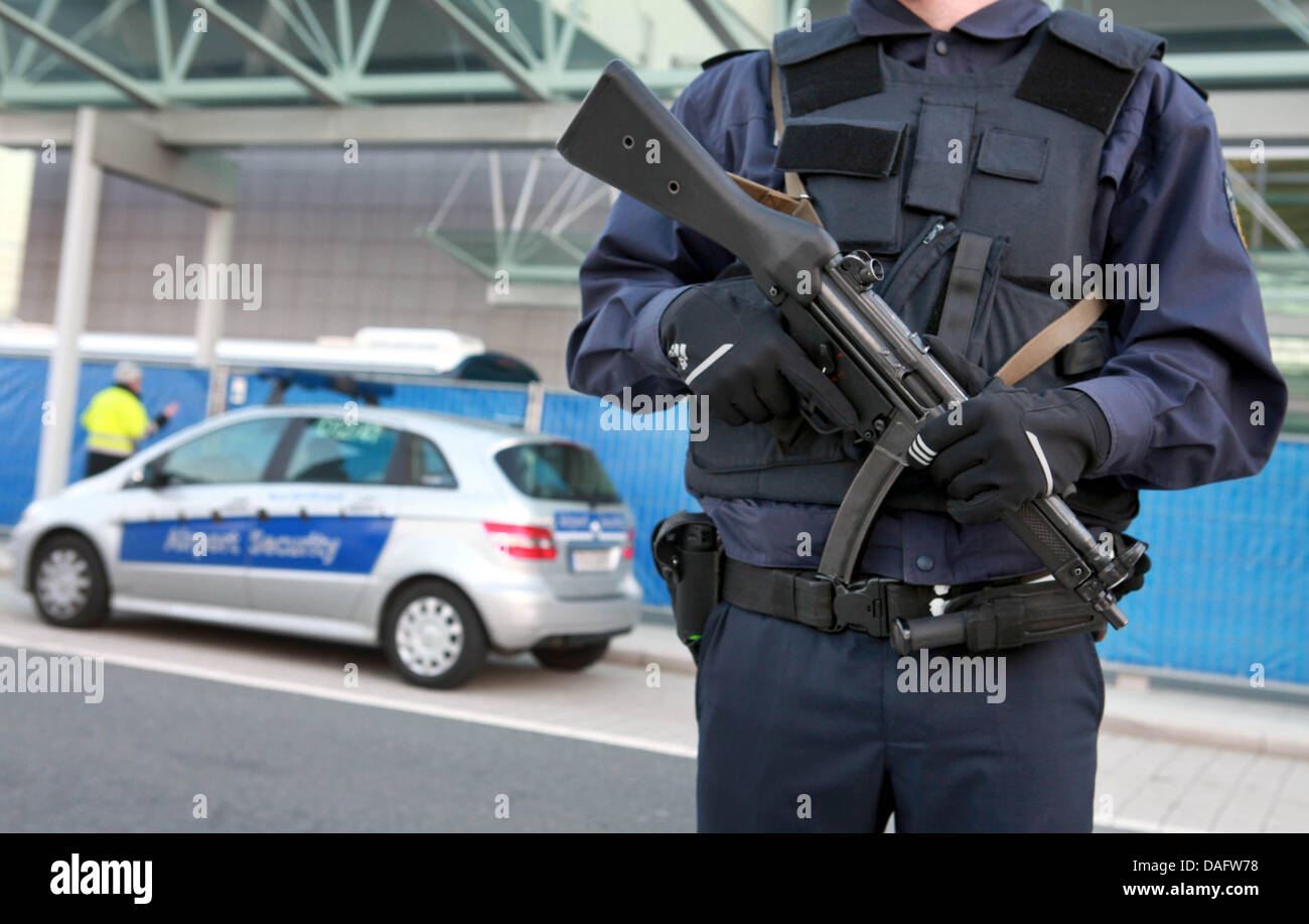A German police officer armed with a machine gun stands in front of a ...