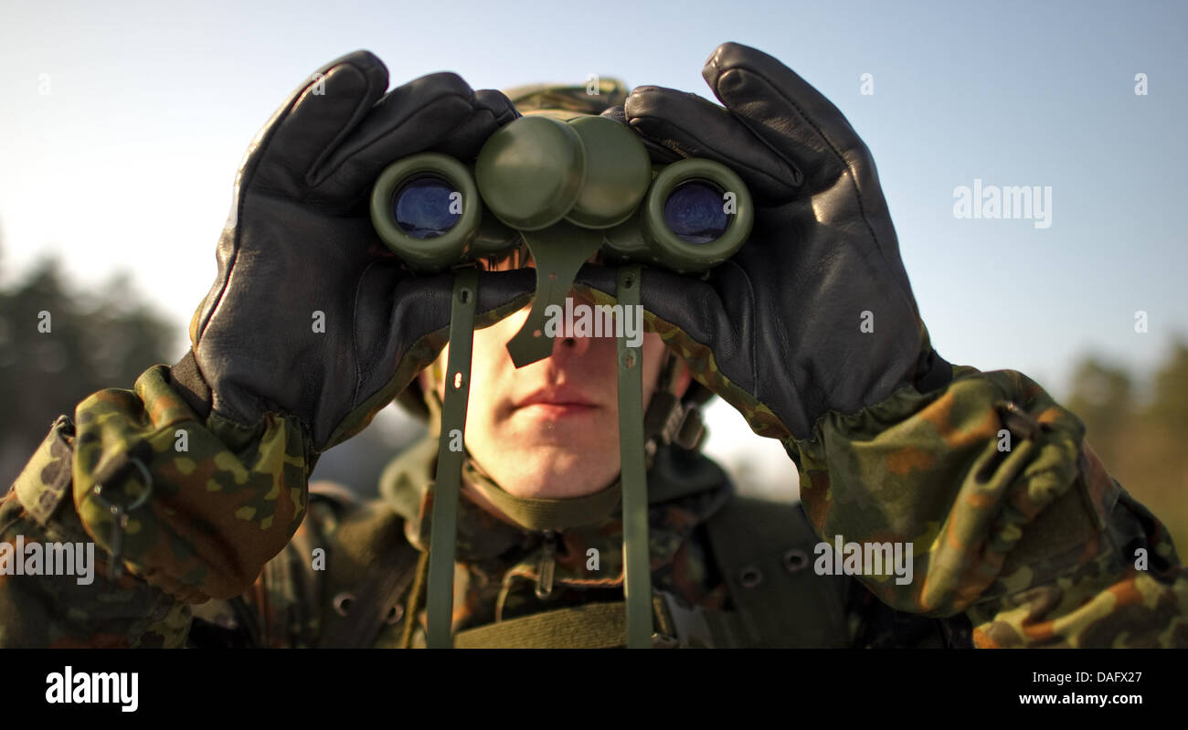 A German Bundeswehr conscript looks through field glasses at ...