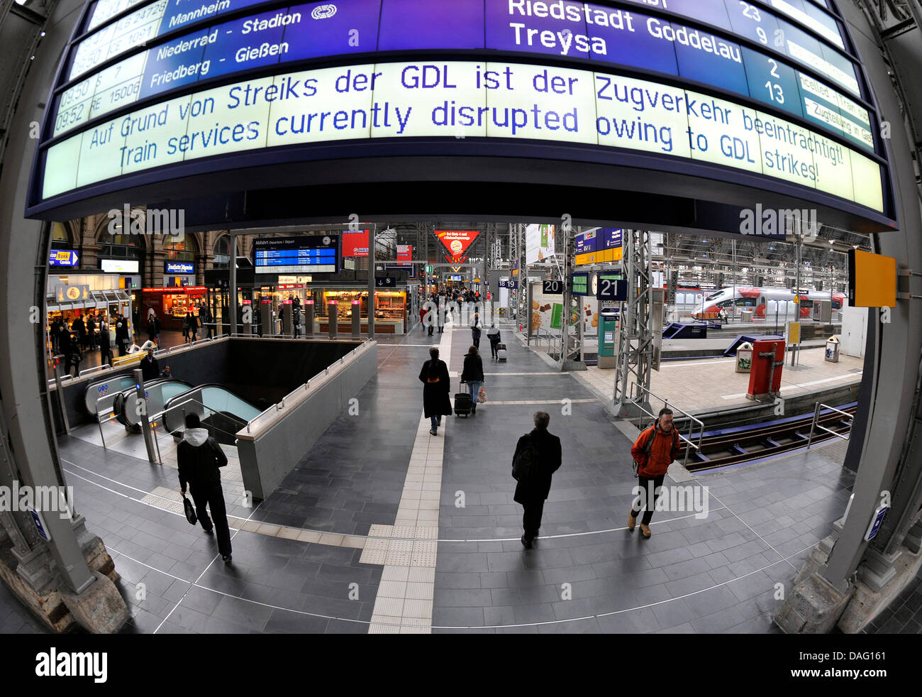 Passengers walk along a platform below a destination board at the main ...
