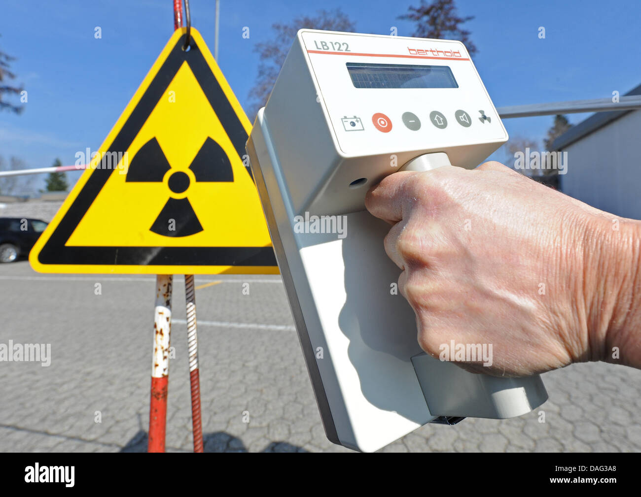 A Geiger counter is held in front of a sign warning from radioactivity ...