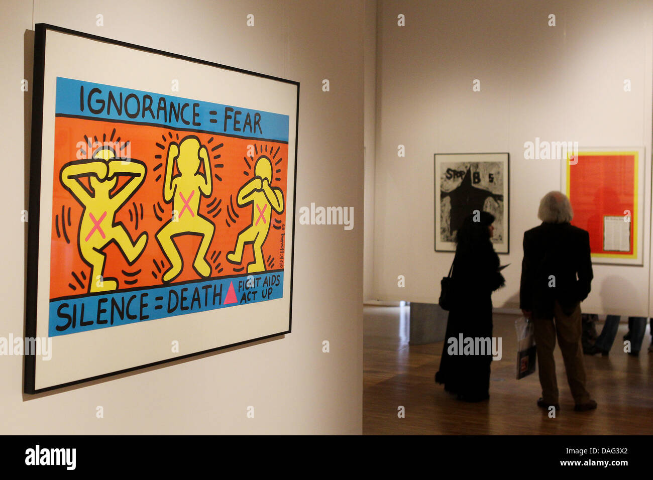 A visitors observes the poster 'Ignorance = Fear, Silence = Death' (l-r ...