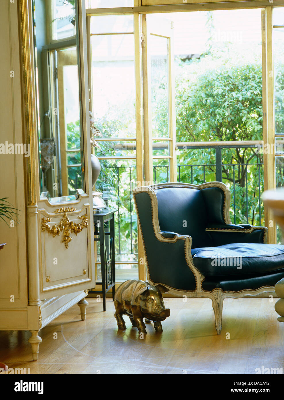 Conservatory with large bronze pig on floor beside armchair in front of ...