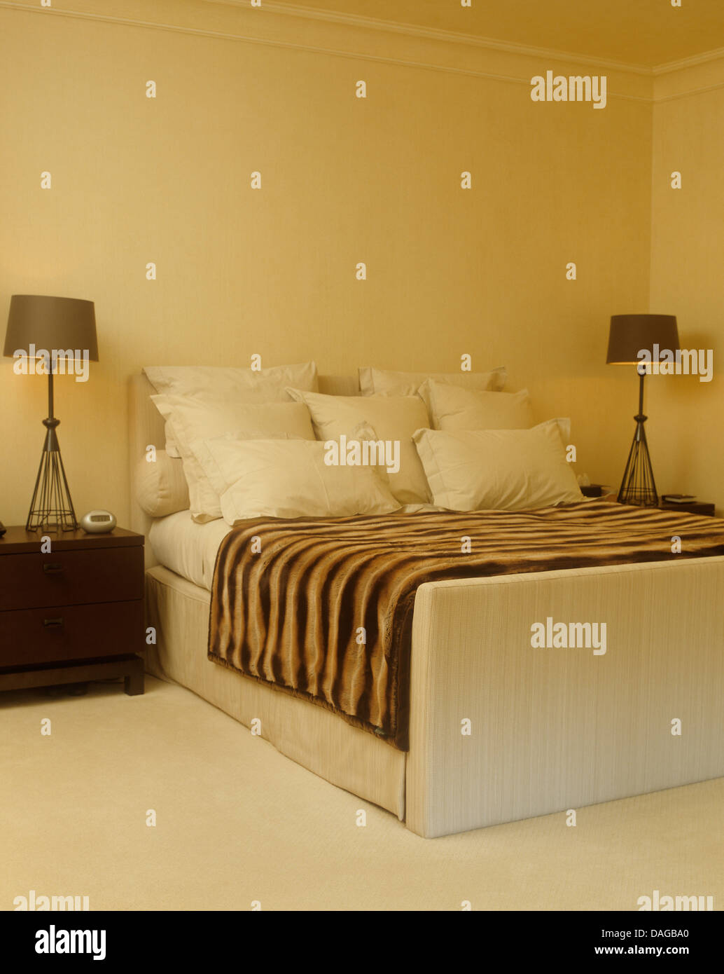 Faux animal skin throw on suede upholstered bed piled with pillows in ...