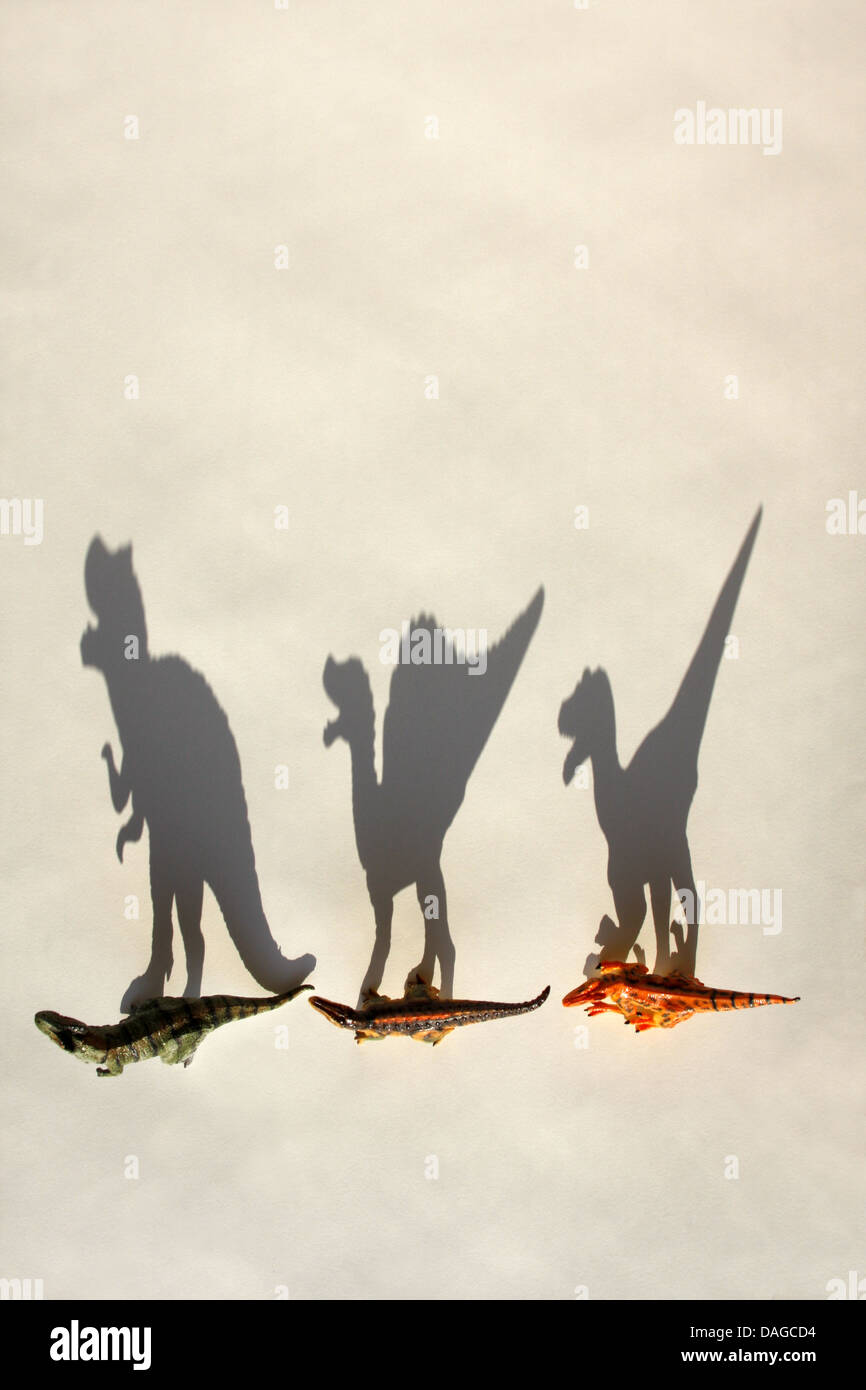 Three toy dinosaur predators in a row on white background with shadows ...