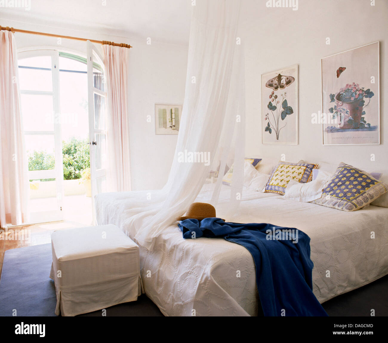White mosquito net above bed with white bedspread in white coastal ...