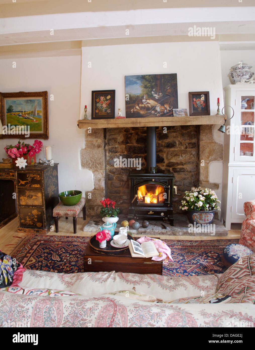 Pictures on wooden mantelpiece above fireplace with lit wood burning ...