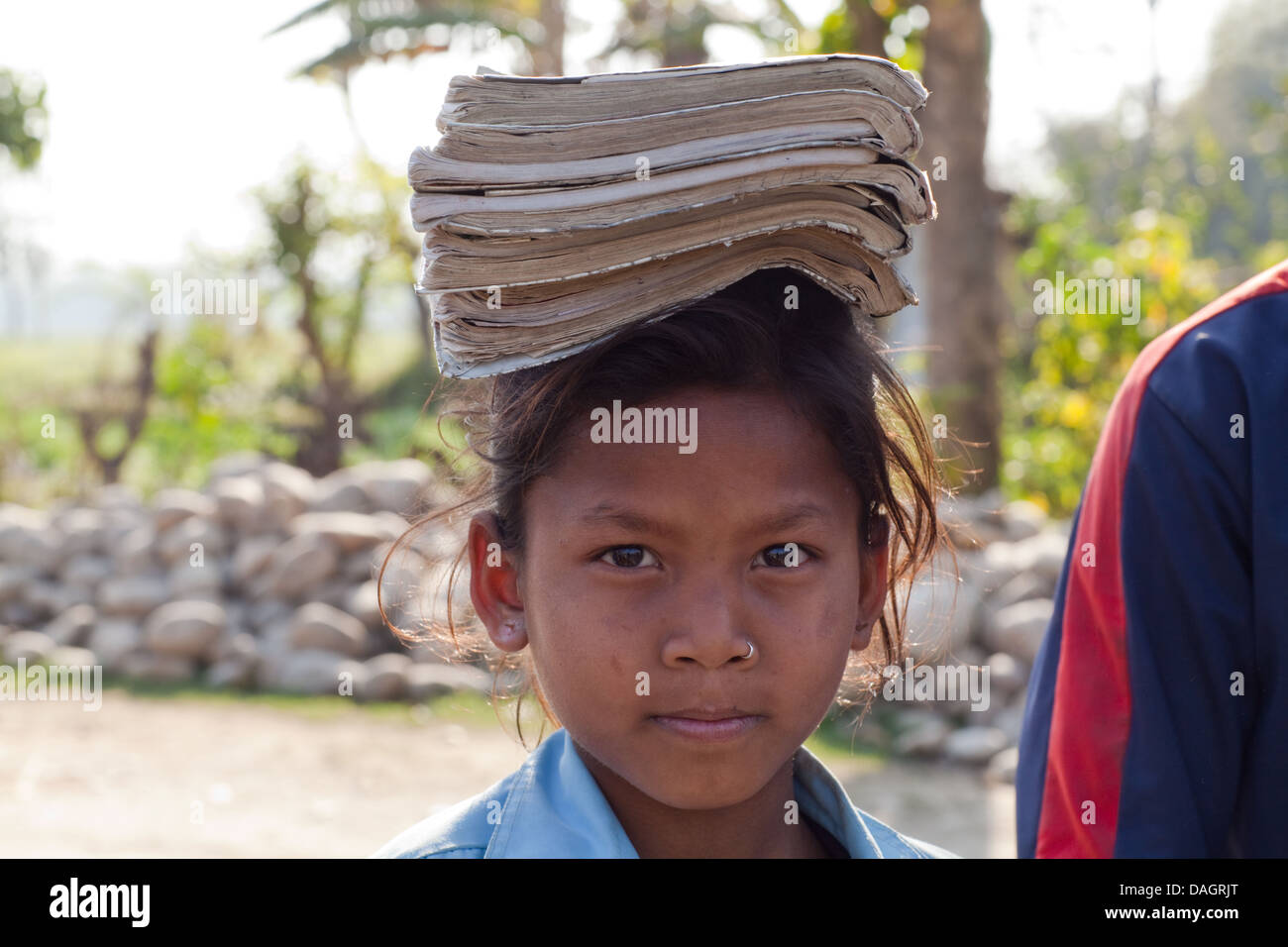 Tharu School Girl carrying her well used books balanced on her head ...