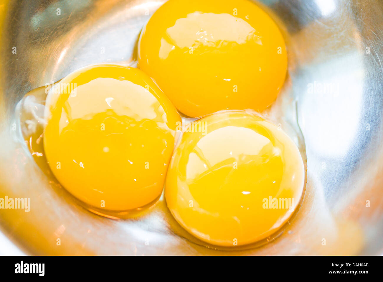 Three egg yolks in metal bowl Stock Photo - Alamy