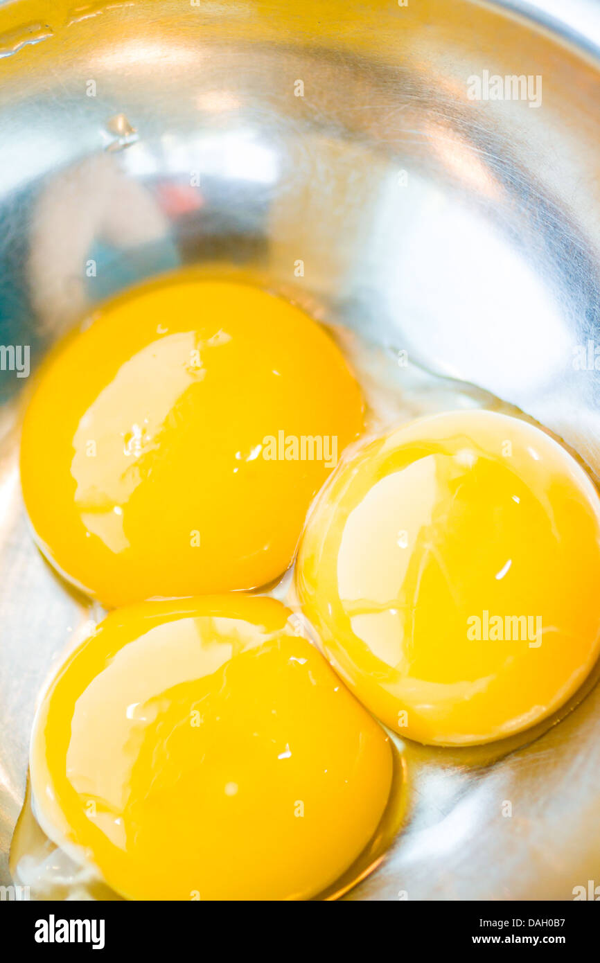 Three egg yolks in metal bowl Stock Photo - Alamy