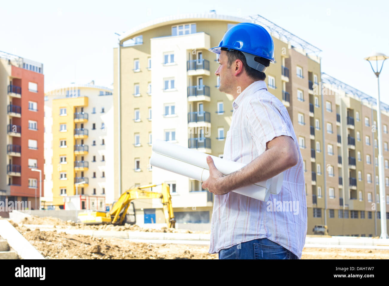 Engineer with blue hard hat holdind project on the construction site Stock Photo - Alamy