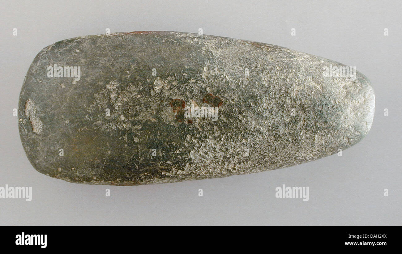 This axe head is crafted from stone, demonstrating early tool-making ...