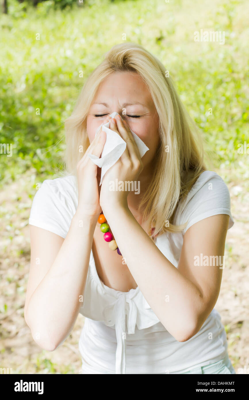 Young woman blowing nose outdoor, pollen allergy Stock Photo - Alamy