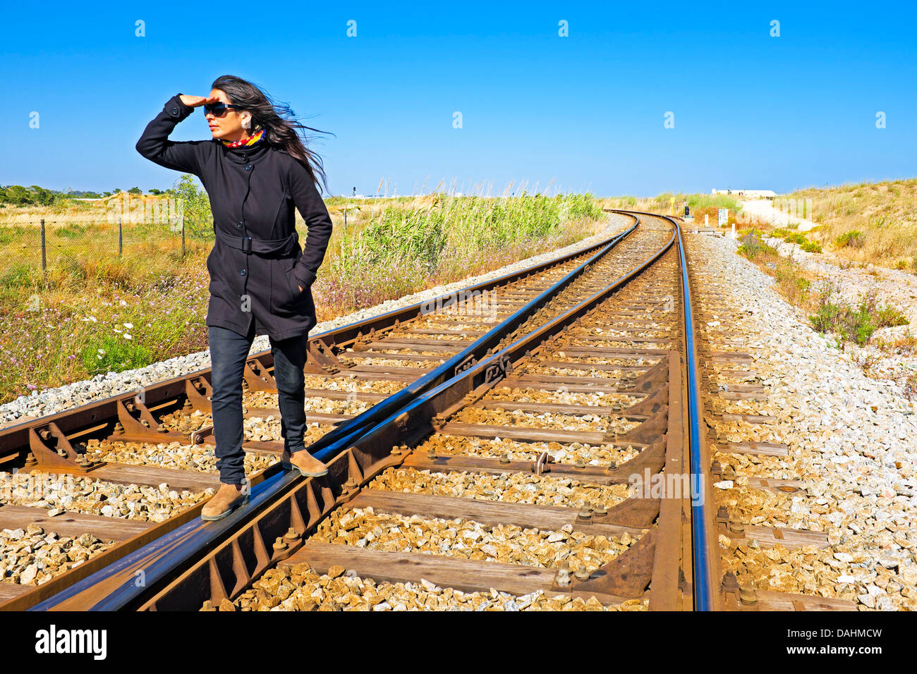Young woman waiting at a railroad track Stock Photo - Alamy