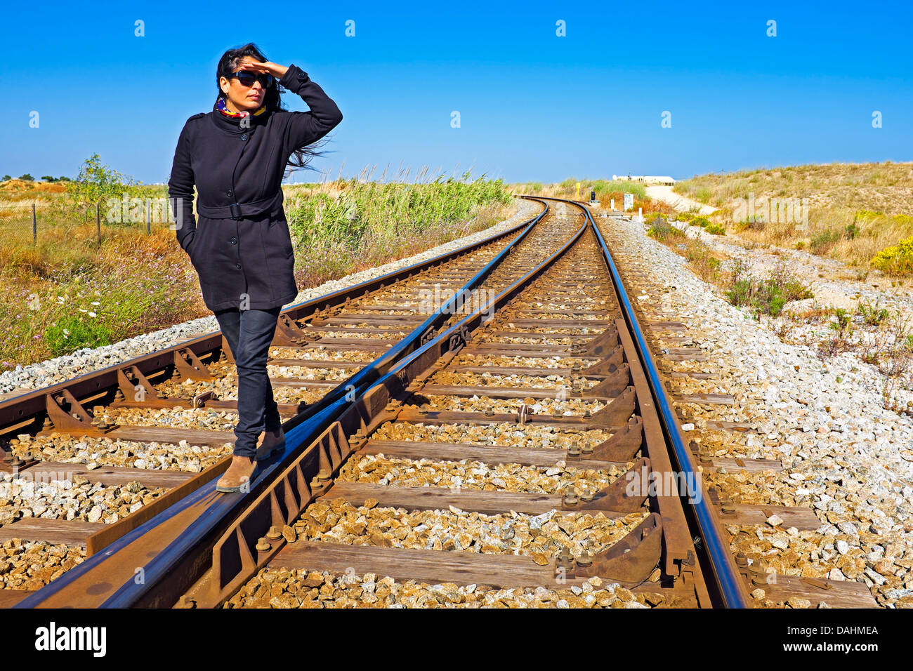 Woman looking for the train at a railroad track Stock Photo - Alamy
