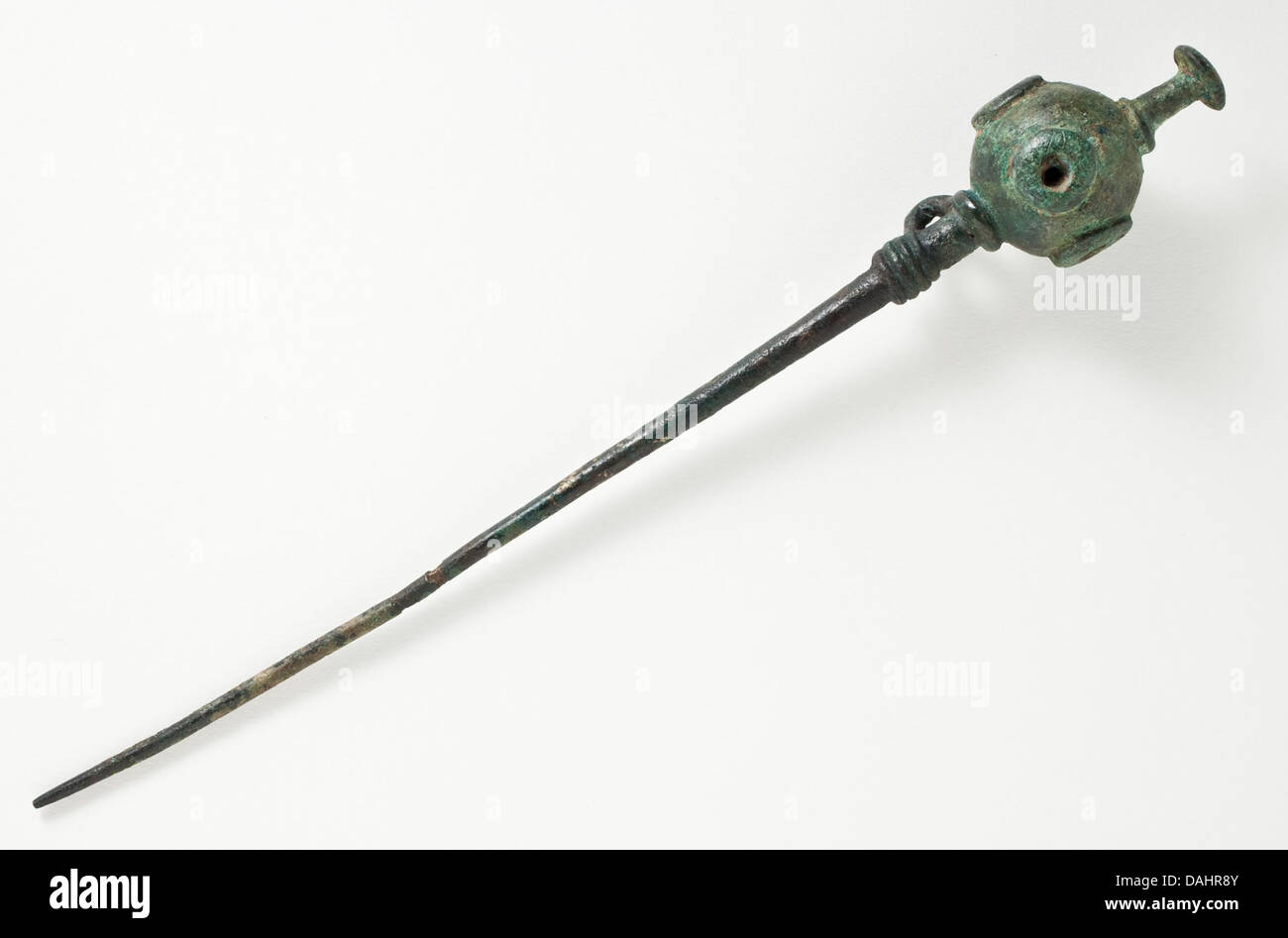 This ancient pin, crafted from bronze, features a circular design ...