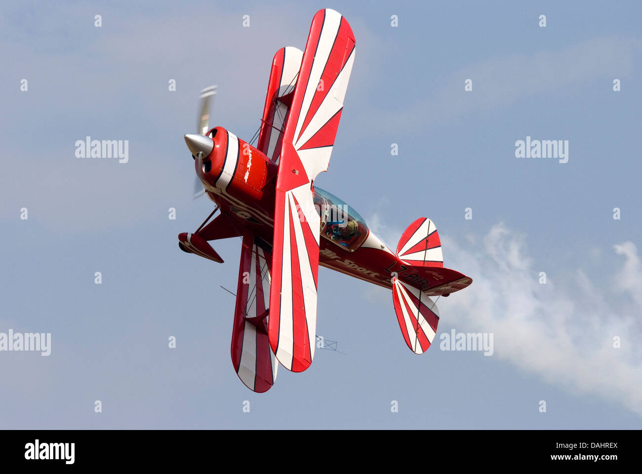 Aerial display by red biplane against blue afternoon sky Stock Photo ...