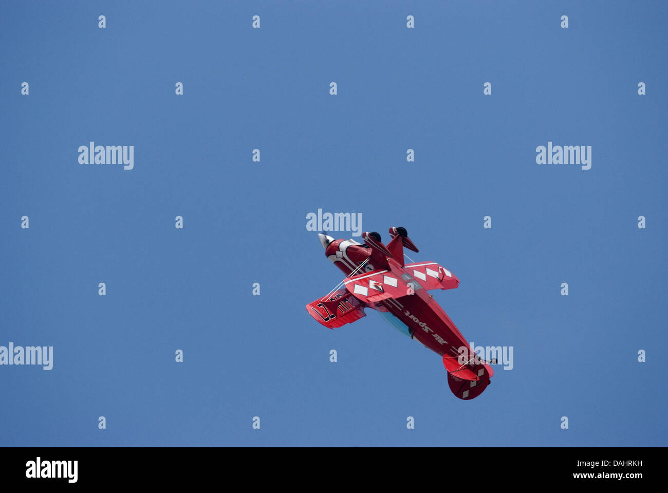 Aerial display by red biplane against blue afternoon sky Stock Photo ...