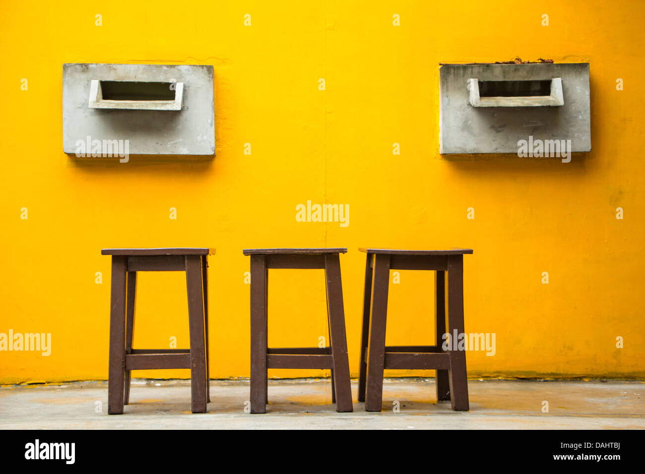 Three chair on concrete stage and yellow wall Stock Photo - Alamy