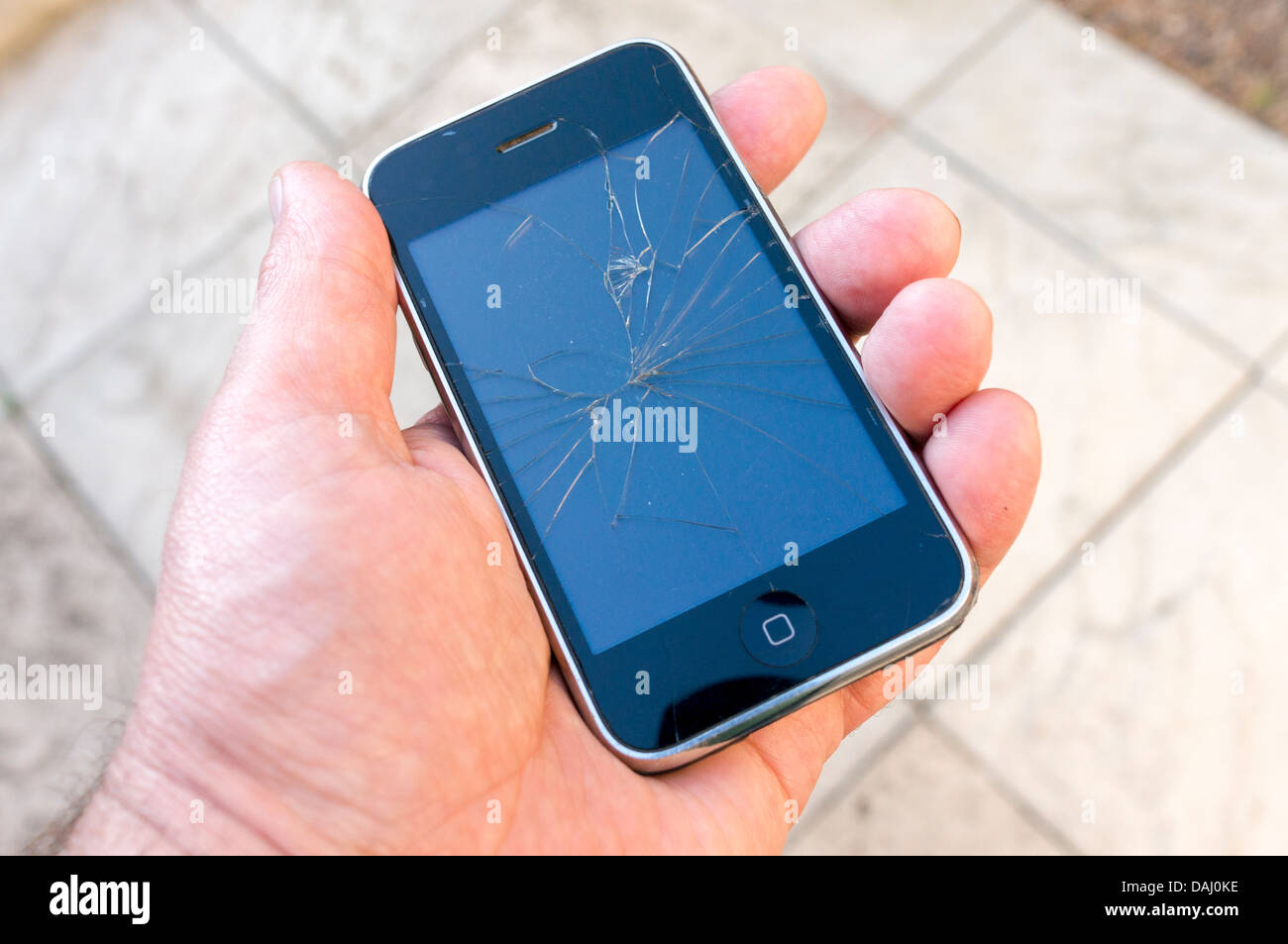 Mans hand holding an Apple iPhone with cracked screen Stock Photo - Alamy
