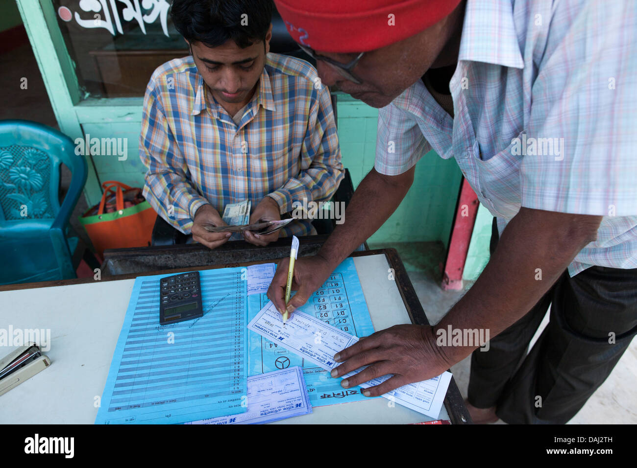 writing and issuing a bus ticket from Srimongol to Dhaka at a table in ...