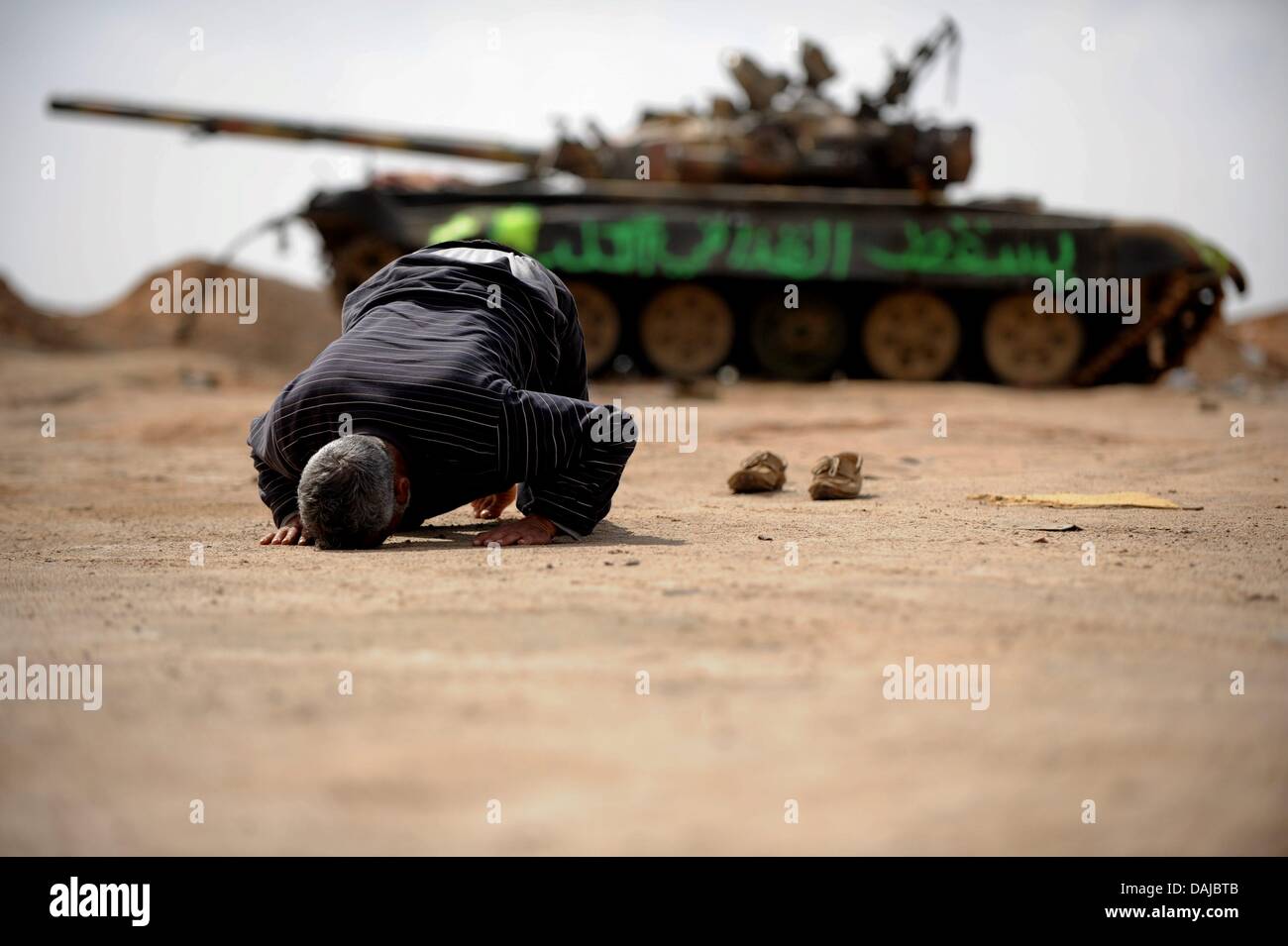 The Libyan insurgent Muftah El Shahomi prays in front of a destroyed ...