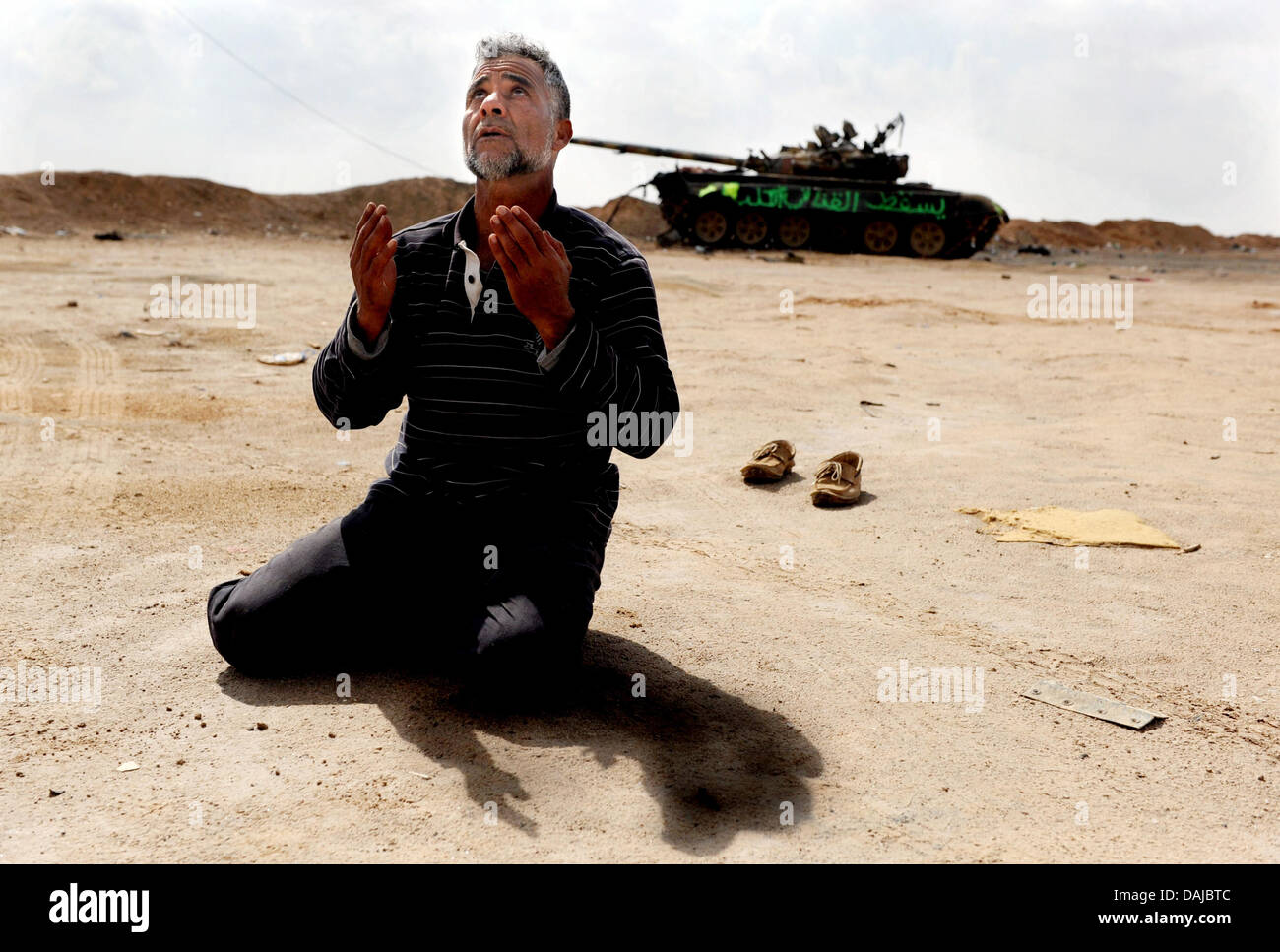 The Libyan insurgent Muftah El Shahomi prays in front of a destroyed ...