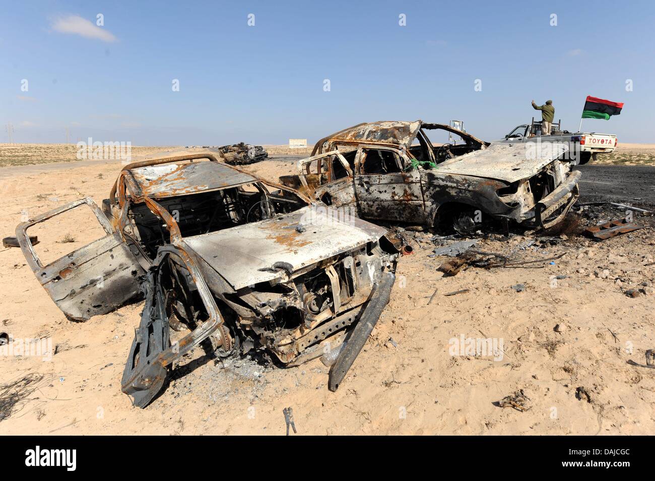 Libyan rebel fighters drive past car wrecks towards the front of the ...