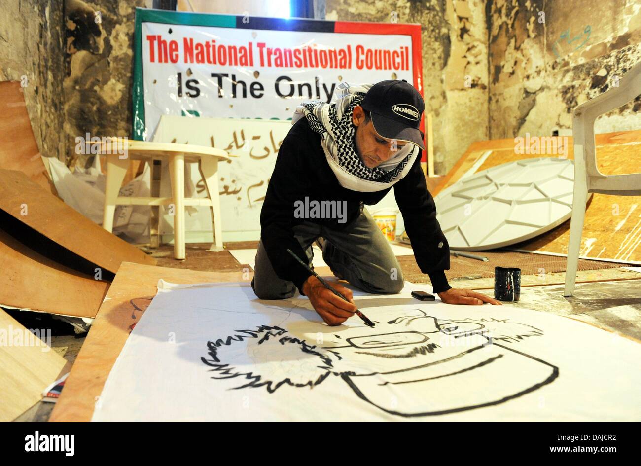 The painter Bilgesim kneels in front of one of his anti-Gaddaffi ...