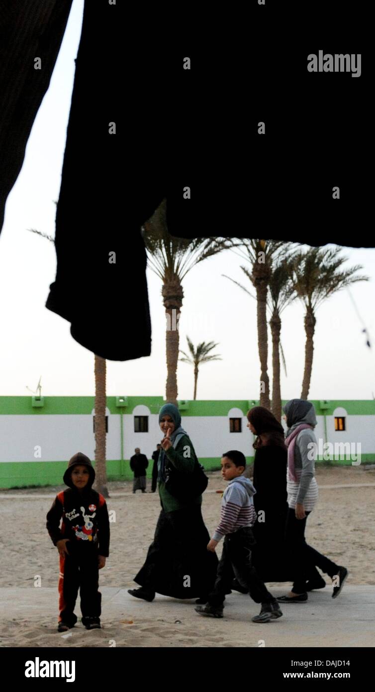 Refugee families walk through a holiday village which has been ...