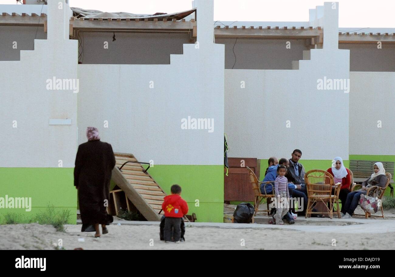 Refugee families walk through a holiday village which has been ...