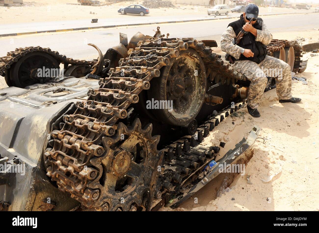 A Libyan rebel sits on the wreck of a tank on the edge of Ajdabiya ...