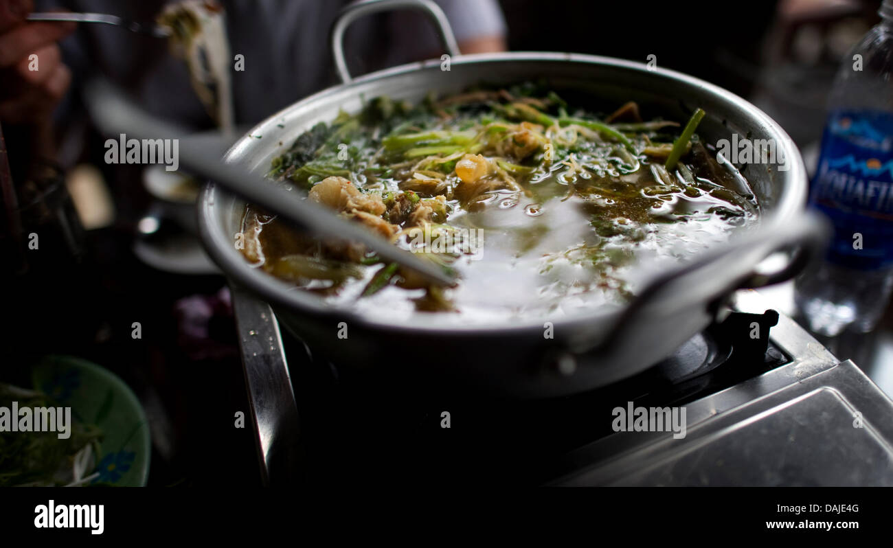 A traditional Vietnamese food boils in a cooking pot on a stove in Ho ...