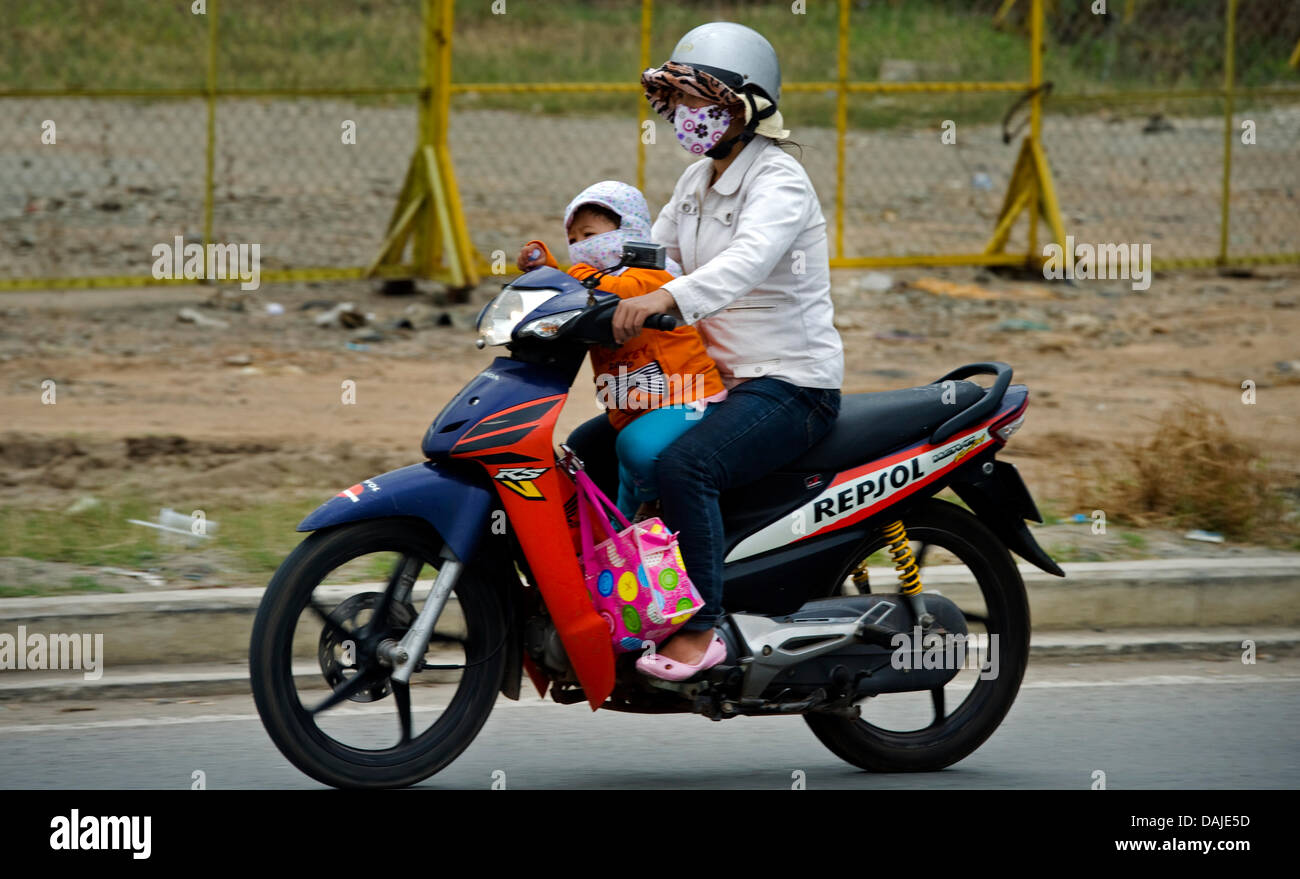 A mother rides with her little one on a motorcycle on a street in Ho ...