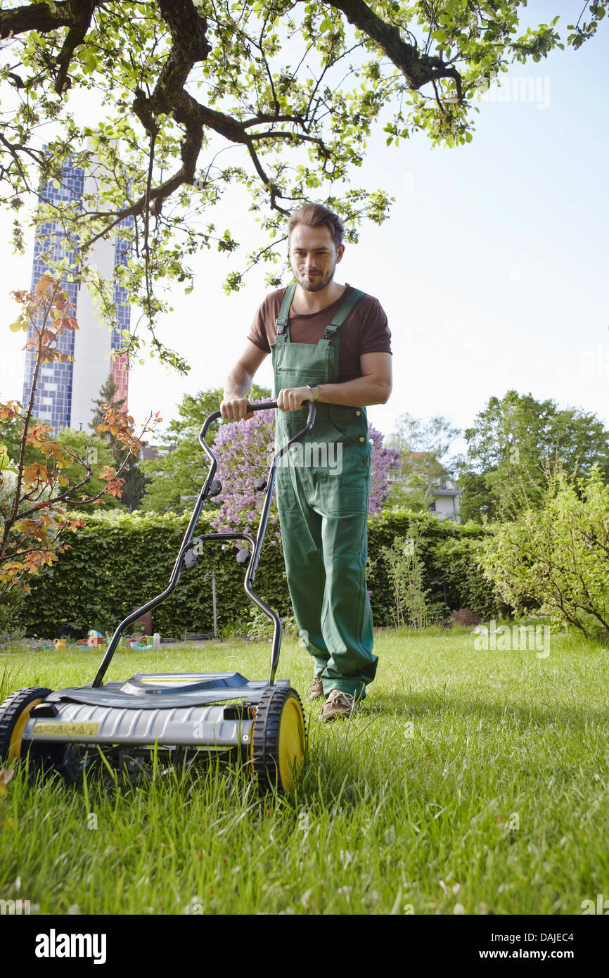 Germany, Cologne, Young man mowing lawn with push mower Stock Photo - Alamy
