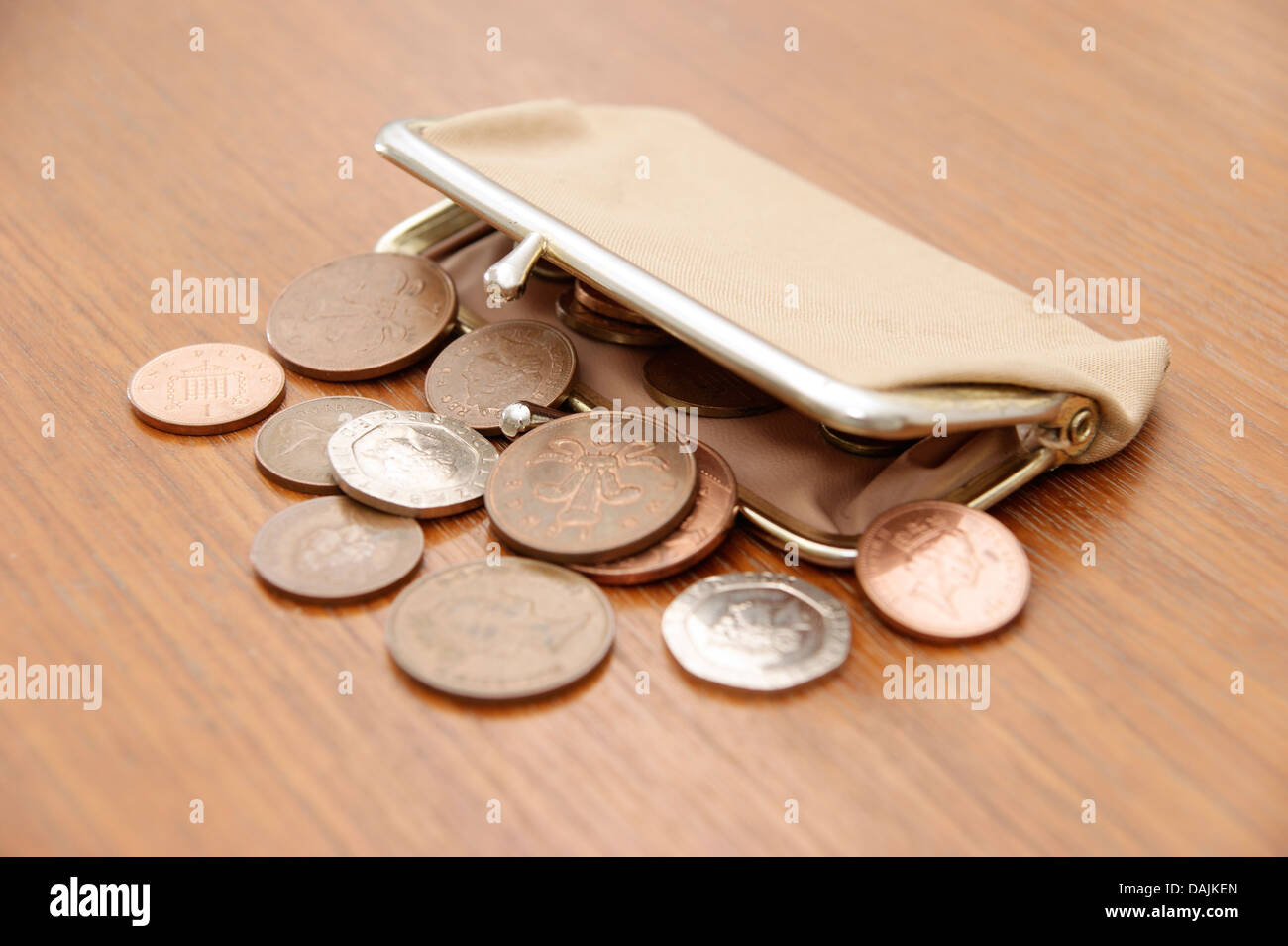 A purse filled with coins (British sterling money) spilling out onto a ...