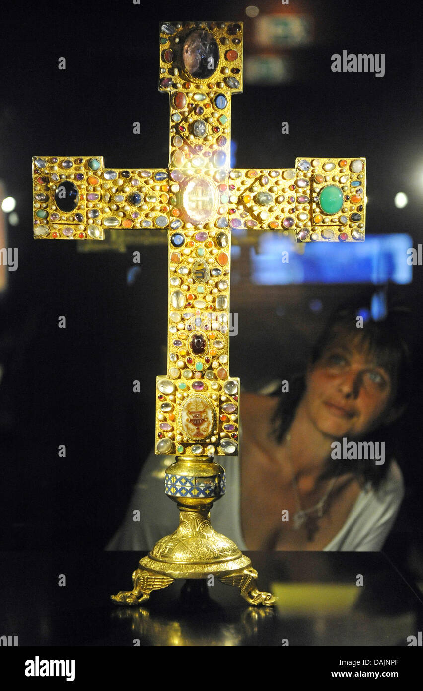 A visitor examines a relic in the shape of a golden cross that was ...