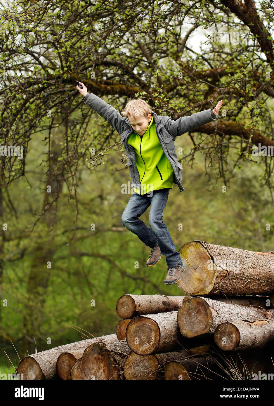 Germany, Baden Wuerttemberg, Boy jumping from wooden logs Stock Photo ...