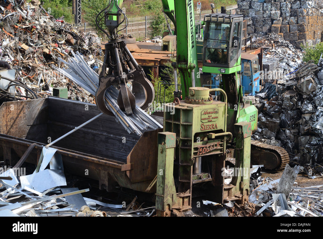 crane loading scrap metal into compactor at scrapyard for baling before ...