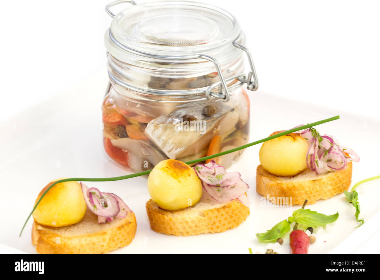 pickled herring in a glass jar with potato canapes Stock Photo - Alamy