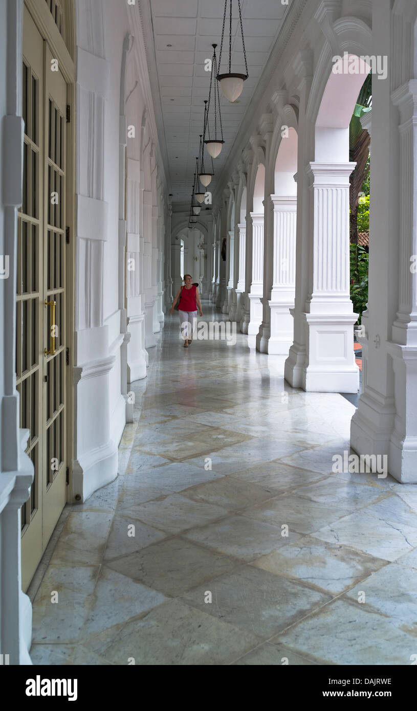 dh RAFFLES SINGAPORE Woman tourist walking column verandah old passage ...