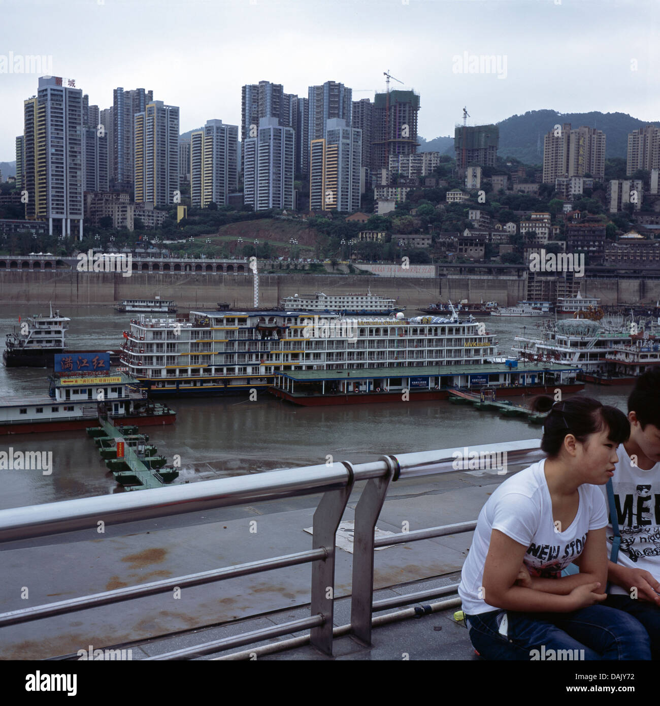 Young couple sit at Chaotianmen dock in Chongqing, China, new houses ...