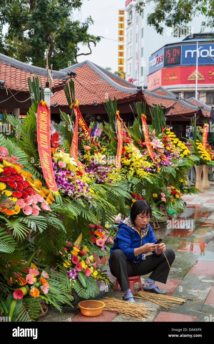 A lady selling flowers at a colorful street flower market in Haiphong ...