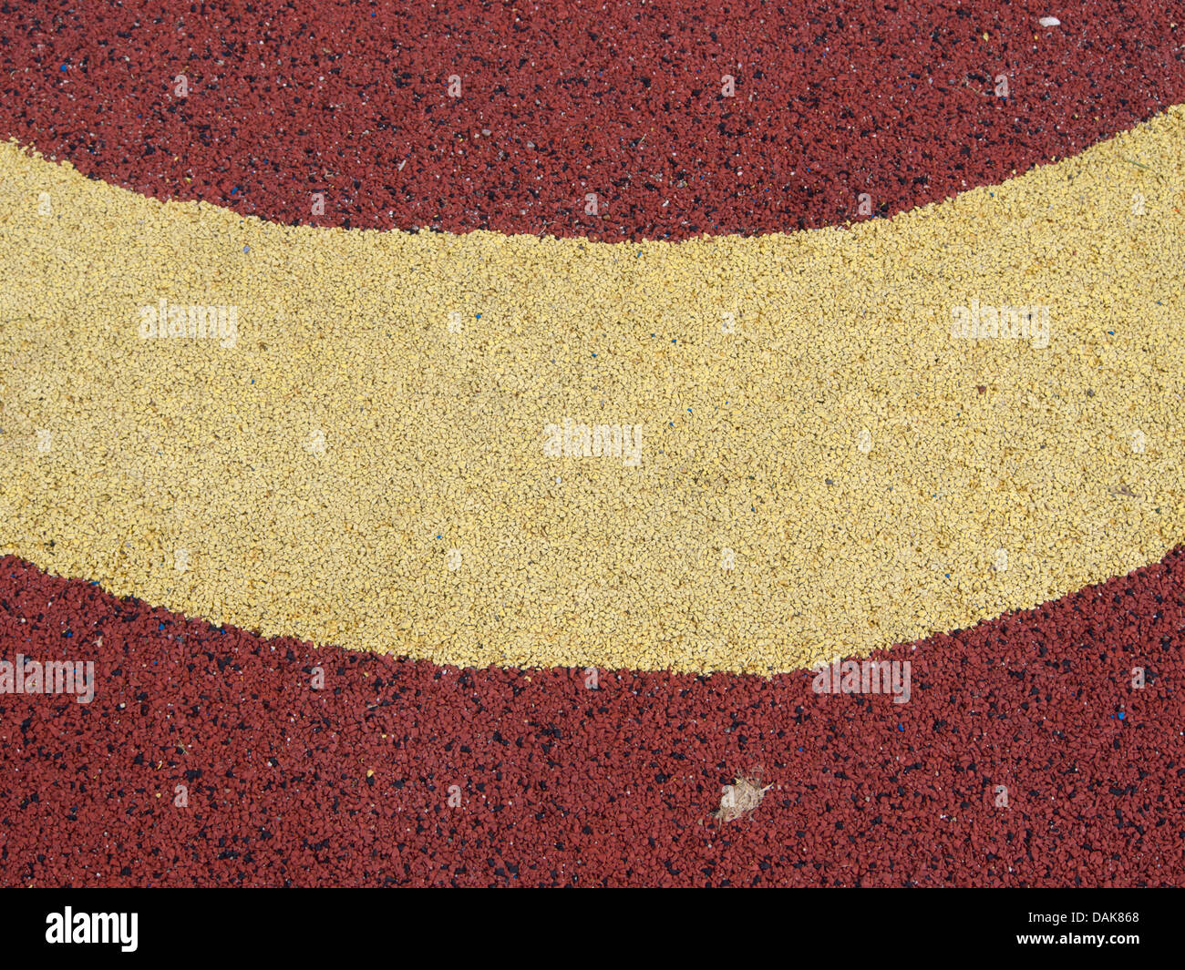 Yellow curve on red tarmac, detail from playground, abstract background ...