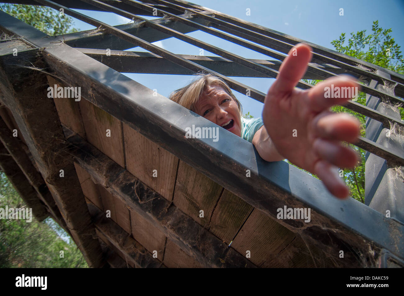 Woman on bridge offering hand up Stock Photo - Alamy