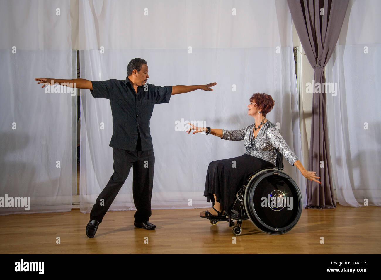 An African American dance teacher instructs handicapped adults perform ...