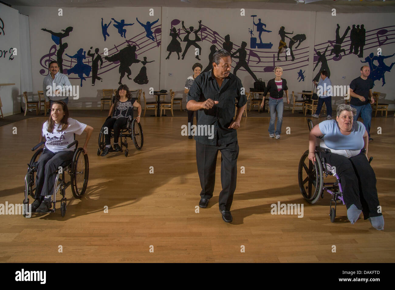 An African American dance teacher instructs handicapped adults perform ...