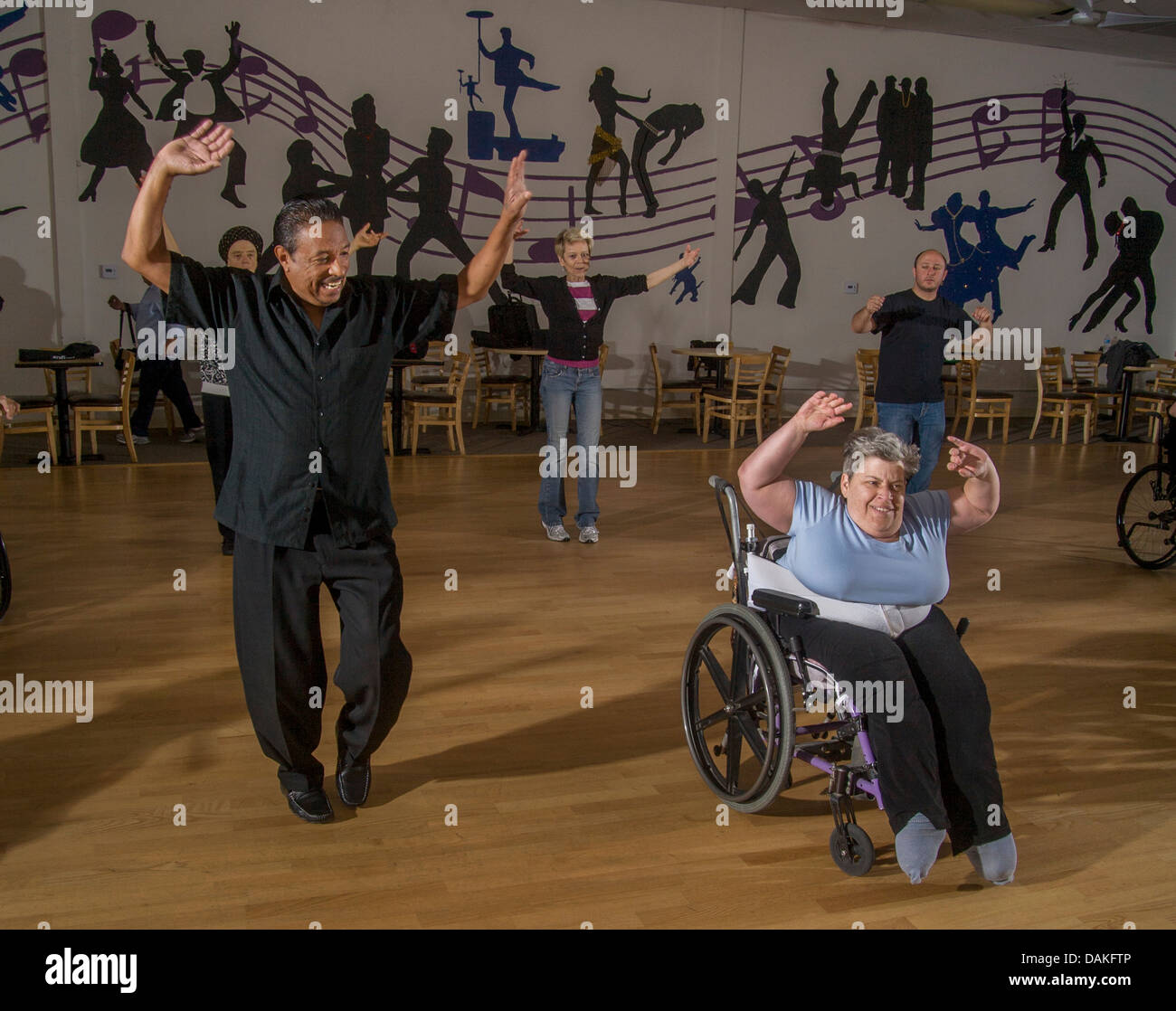 An African American dance teacher instructs handicapped adults perform ...