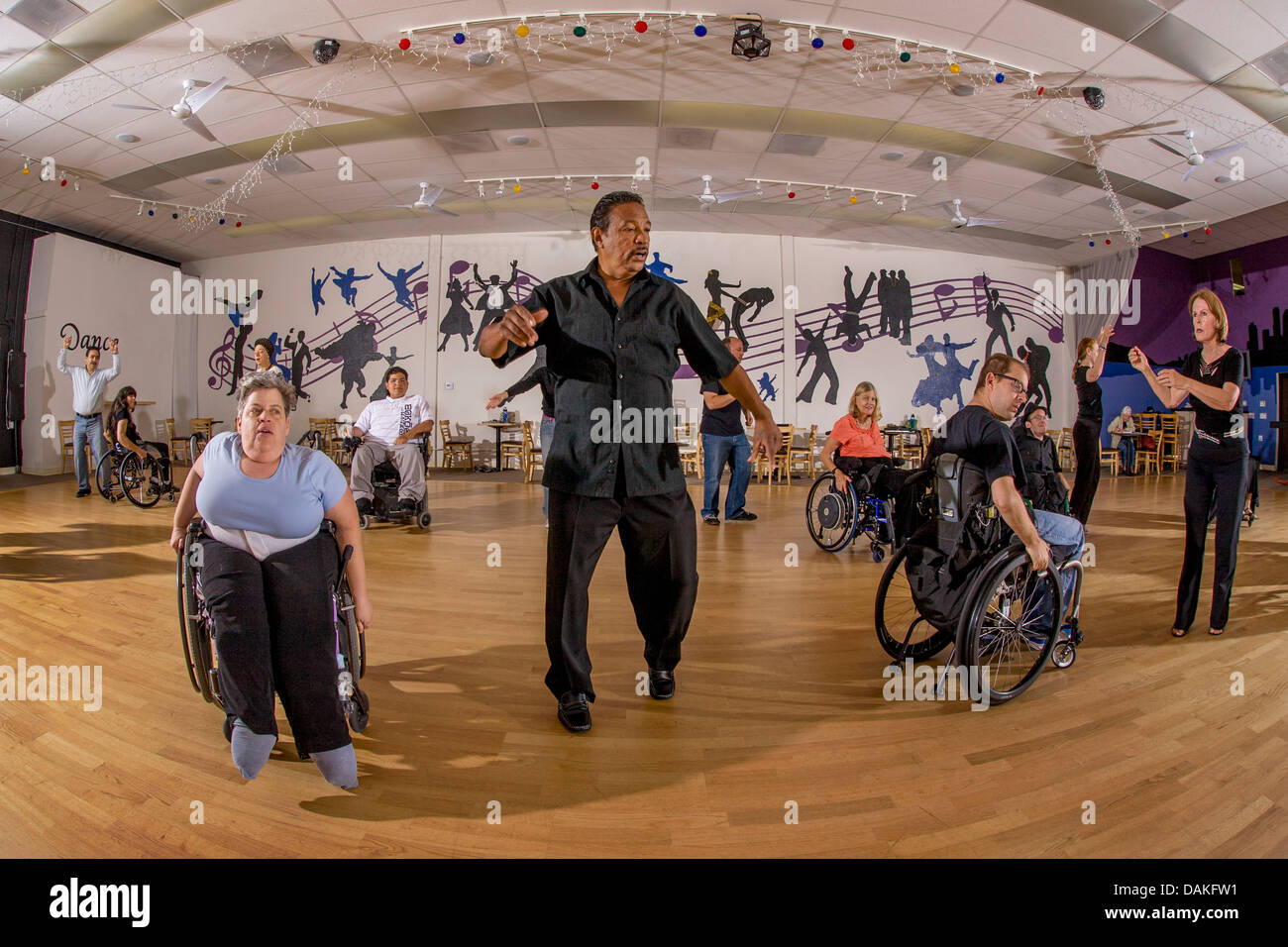 An African American dance teacher instructs handicapped adults perform ...